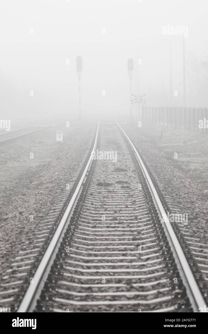 Perspective of railway track disappearing in mist in foggy morning ...