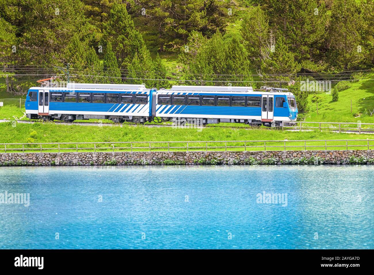 Train passing through Nuria valley against foreground of blue mountain ...