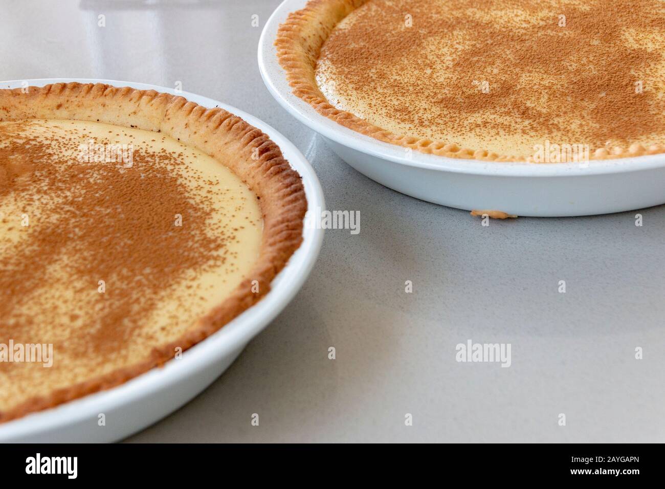 A close up view of two milk tarts in white bowls ready to eat Stock ...