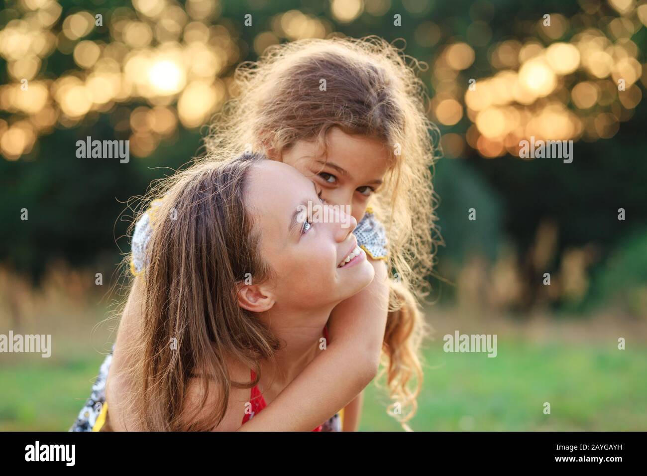 Two Cute little girls hugging and smiling at the countryside. Happy ...
