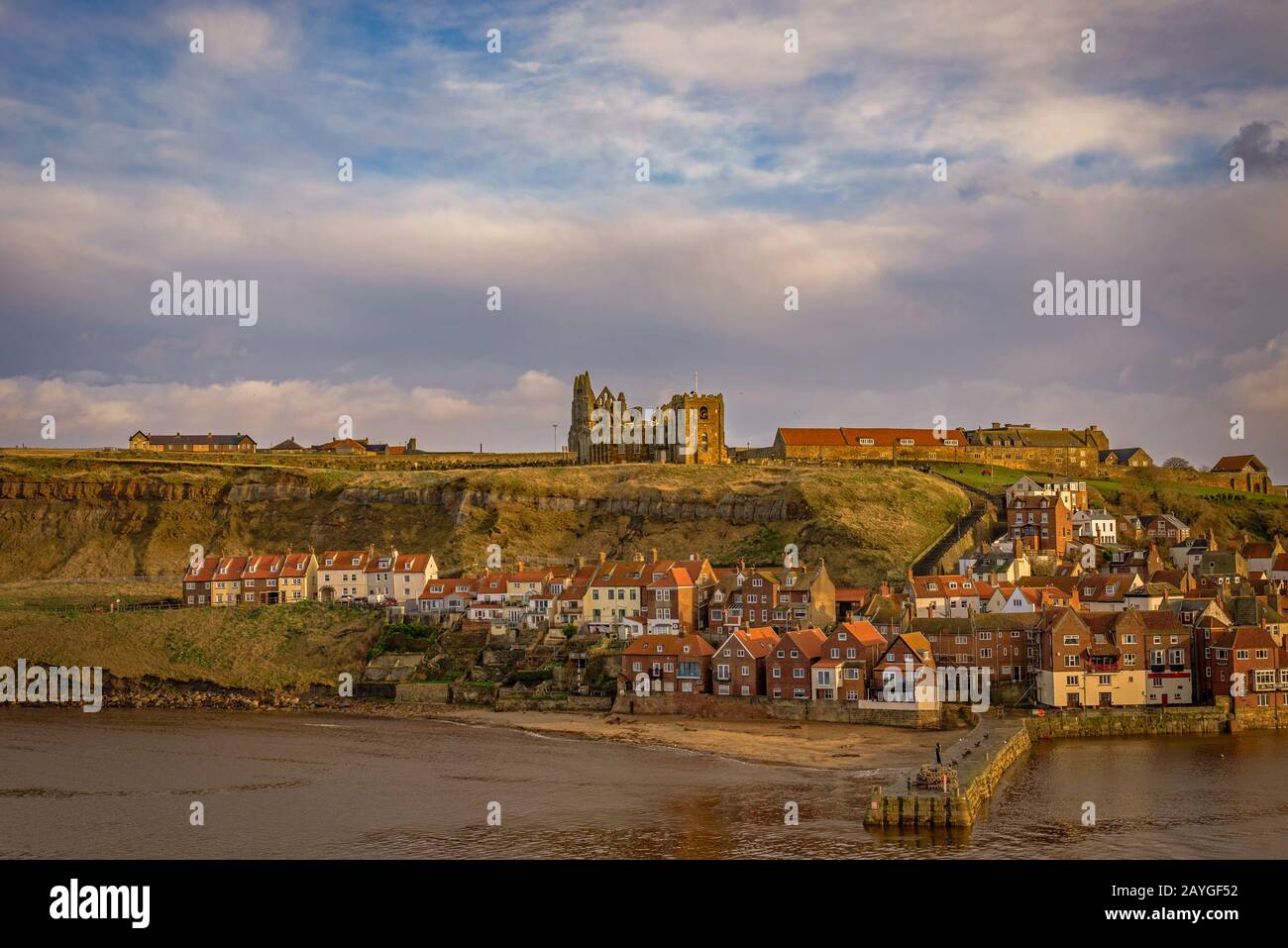 The outer harbour at Whitby. Houses nestle under the cliff with a ...