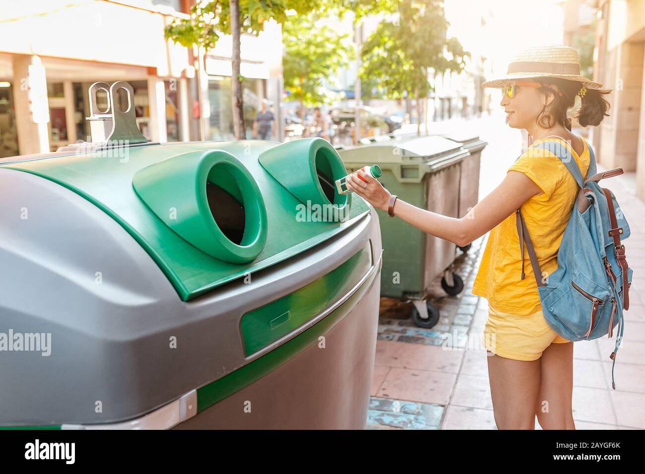 young woman throwing garbage in recycling bin at city street Stock ...