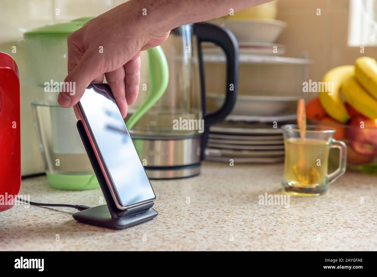 smartphone wireless charging on charging stand on kitchen tabletop ...