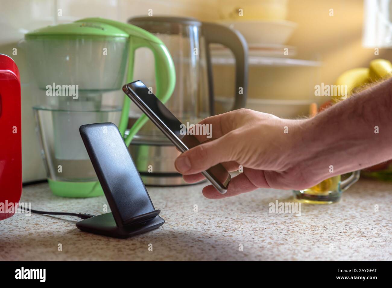 smartphone wireless charging on charging stand on kitchen tabletop ...