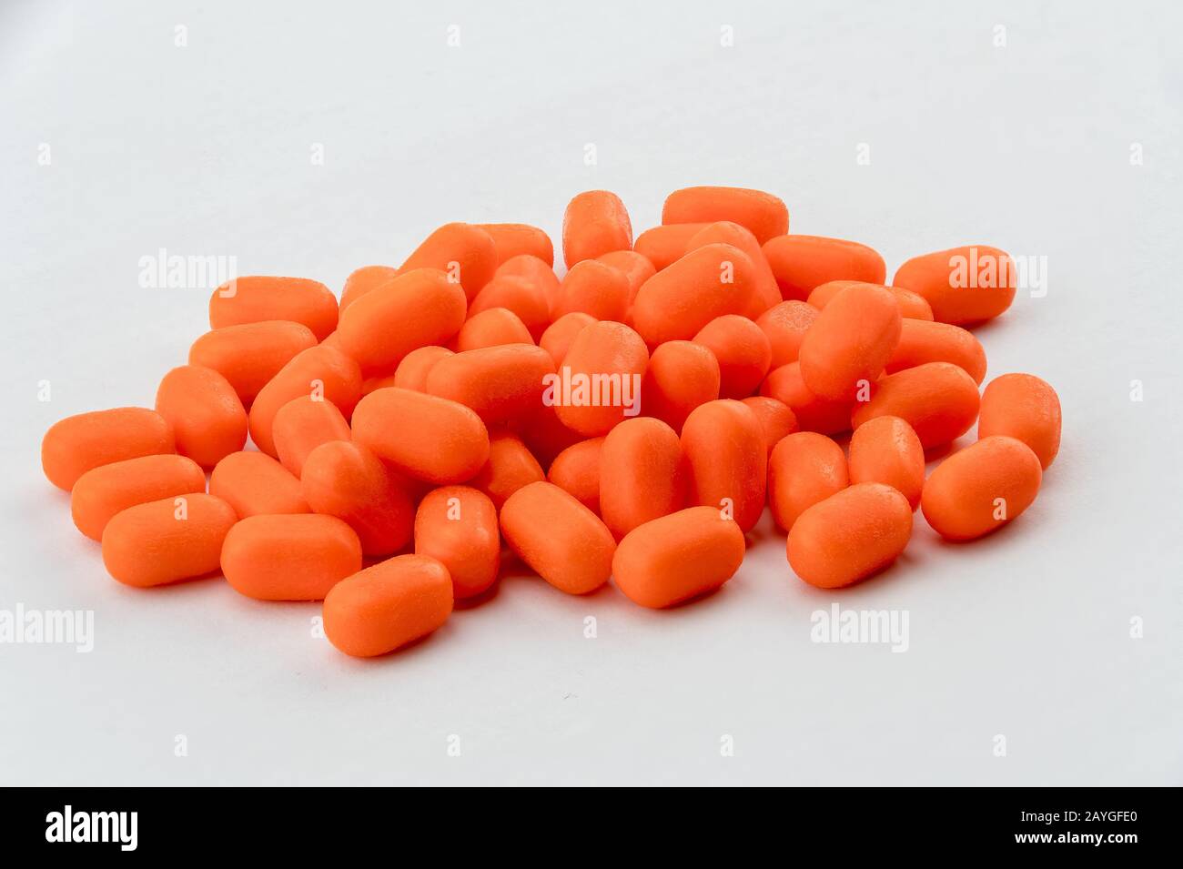 Small orange tic tac candy sweets on a white background Stock Photo - Alamy