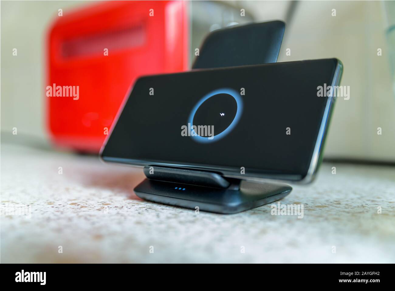 smartphone wireless charging on charging stand on kitchen tabletop ...