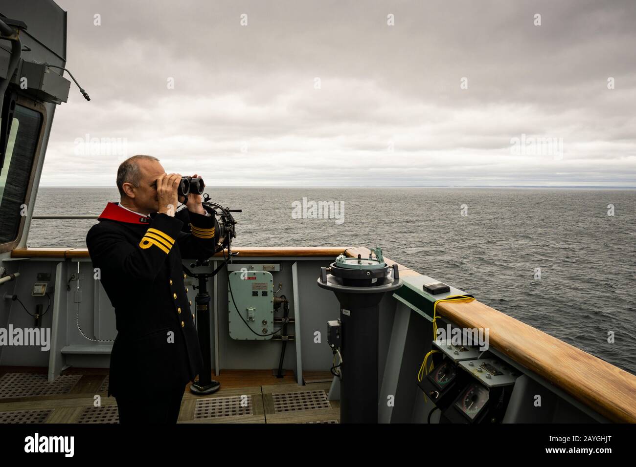 Commander Philip Harper scans the horizon from the bridge of HMS QUEEN ...