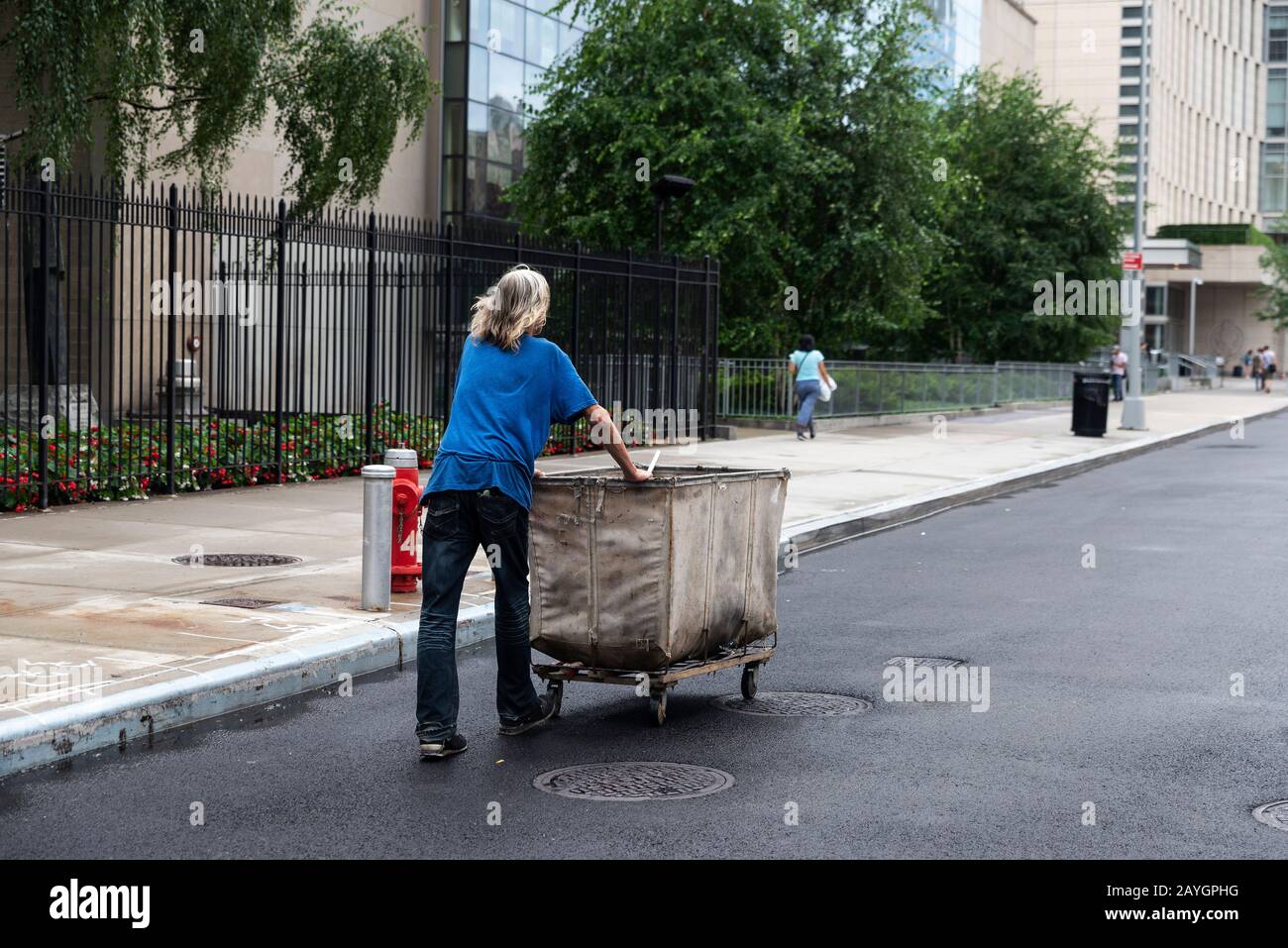 Poor man or homeless pushing a cart on a street in Manhattan, New York ...
