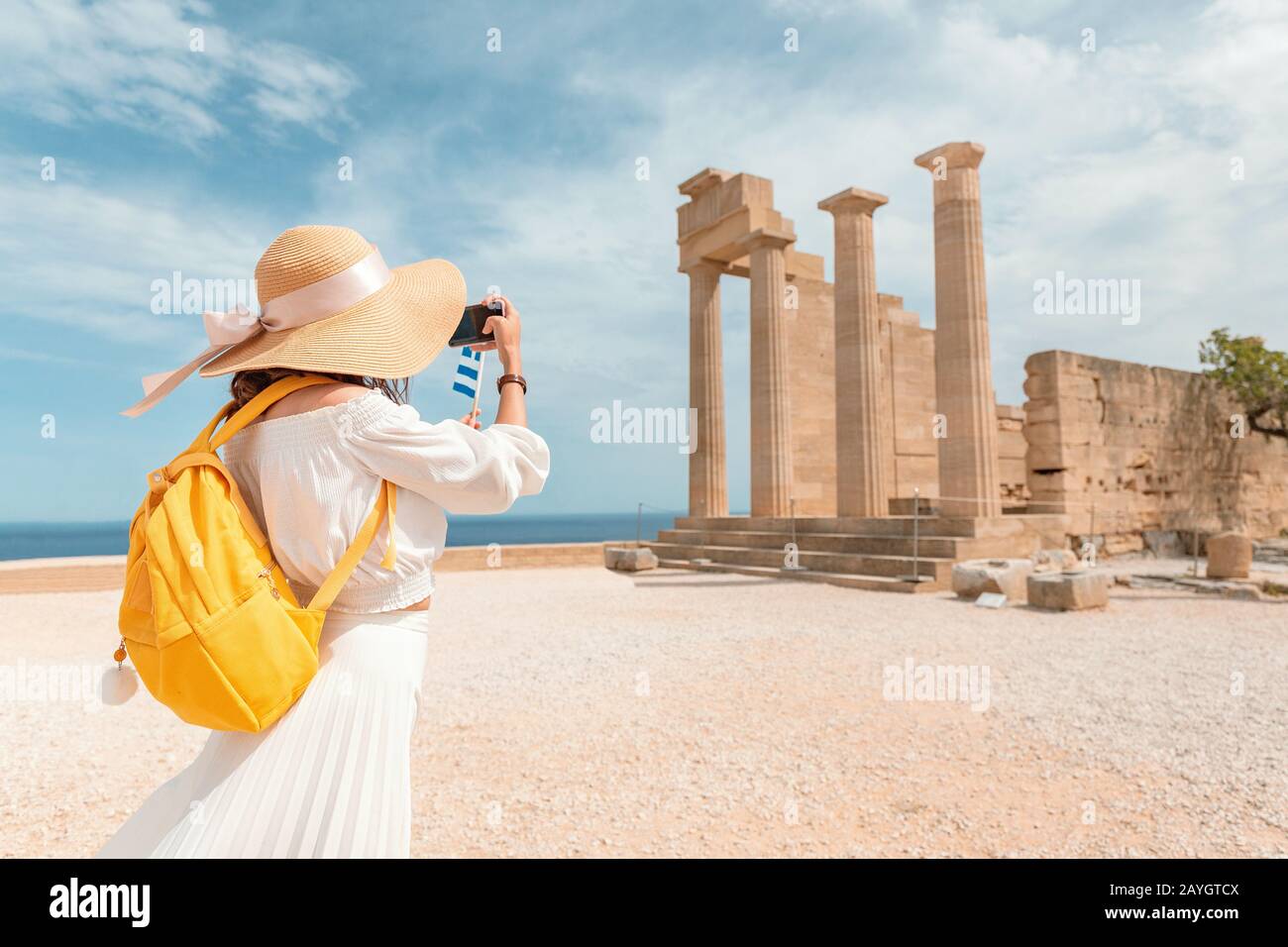 Tourist girl taking photos and selfie of tourist landmark of ancient Acropolis town. Travel ...