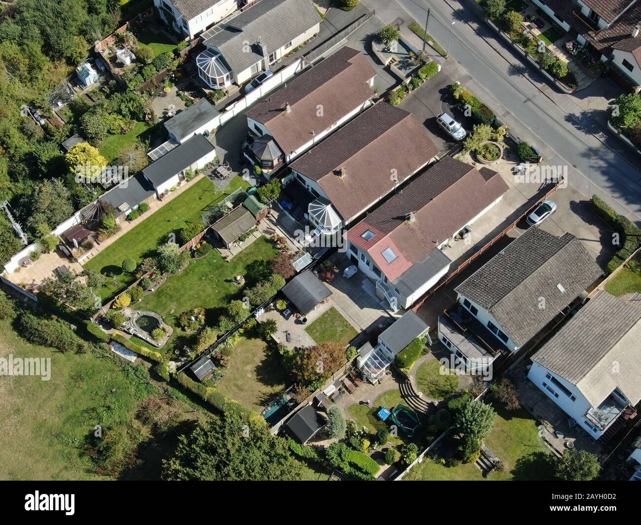 a telephoto aerial view of houses and gardens in a semi-rural area ...