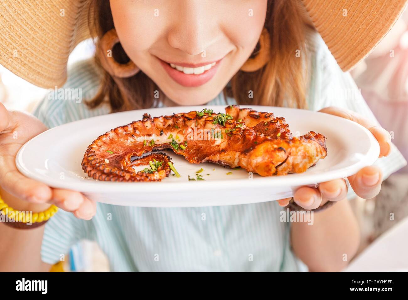 Happy asian woman in hat eating delicious grilled octopus in seafood ...