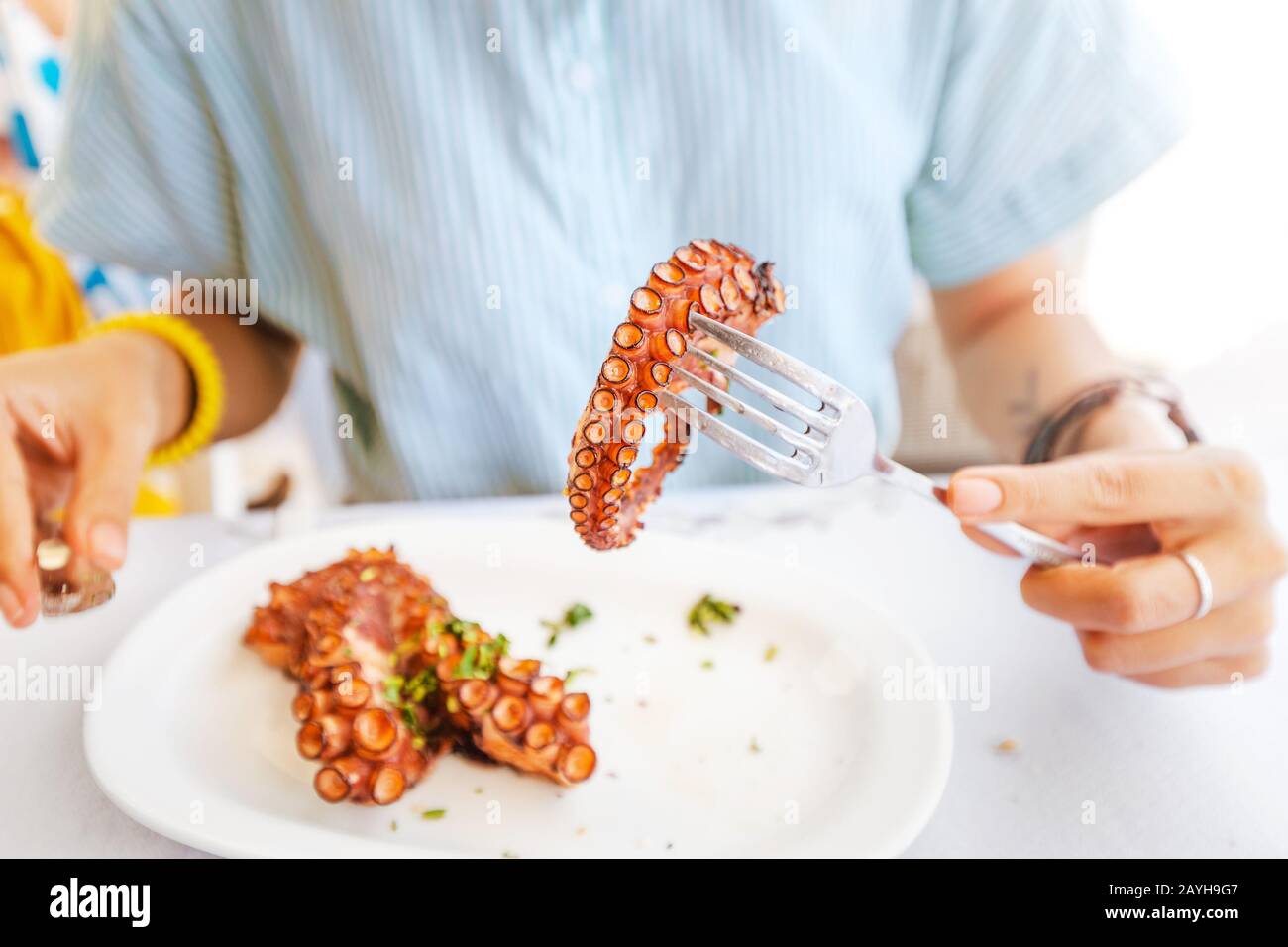 Happy asian woman in hat eating delicious grilled octopus in seafood ...