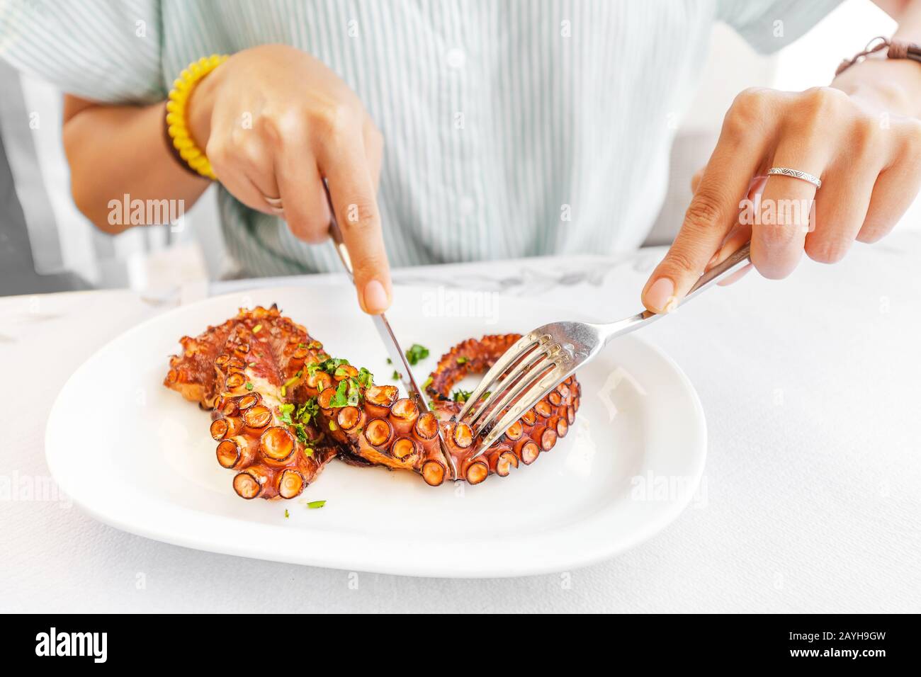 Happy asian woman in hat eating delicious grilled octopus in seafood ...
