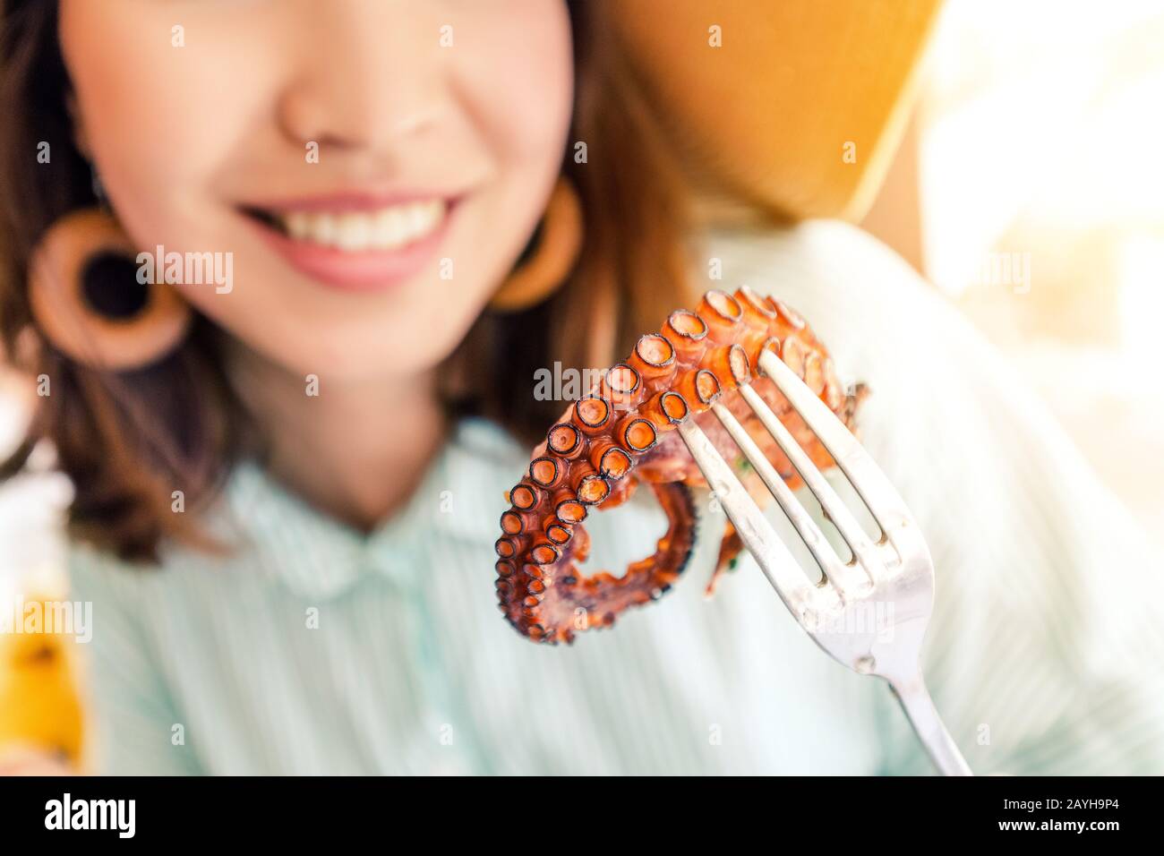 Happy asian woman in hat eating delicious grilled octopus in seafood ...