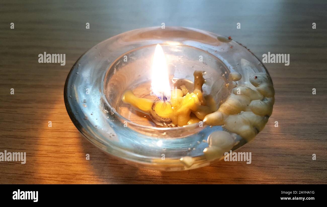 low candle burns in a dirty round glass candlestick, closeup Stock ...