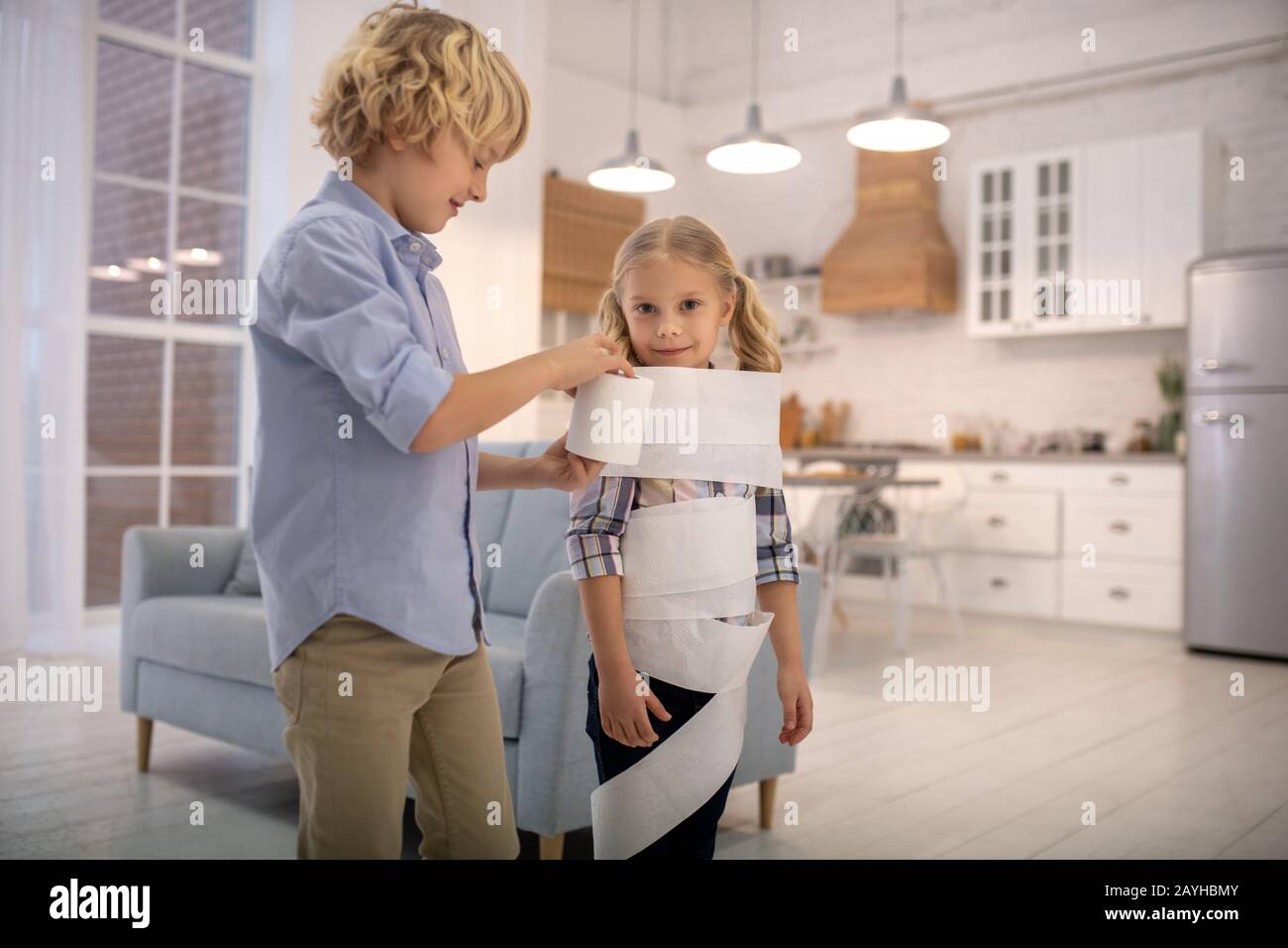 Two kids playing toilet paper mummy game at home and looking ...