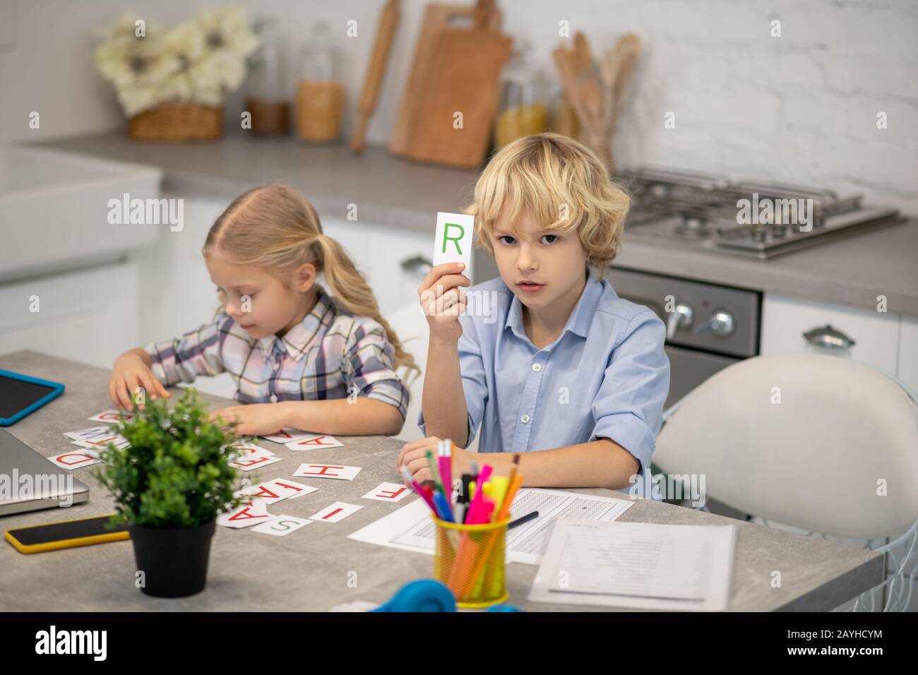 Blond cute boy showing a letter card Stock Photo - Alamy