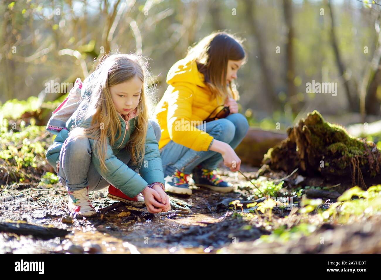 Two cute young sisters having fun by a river on warm spring day ...