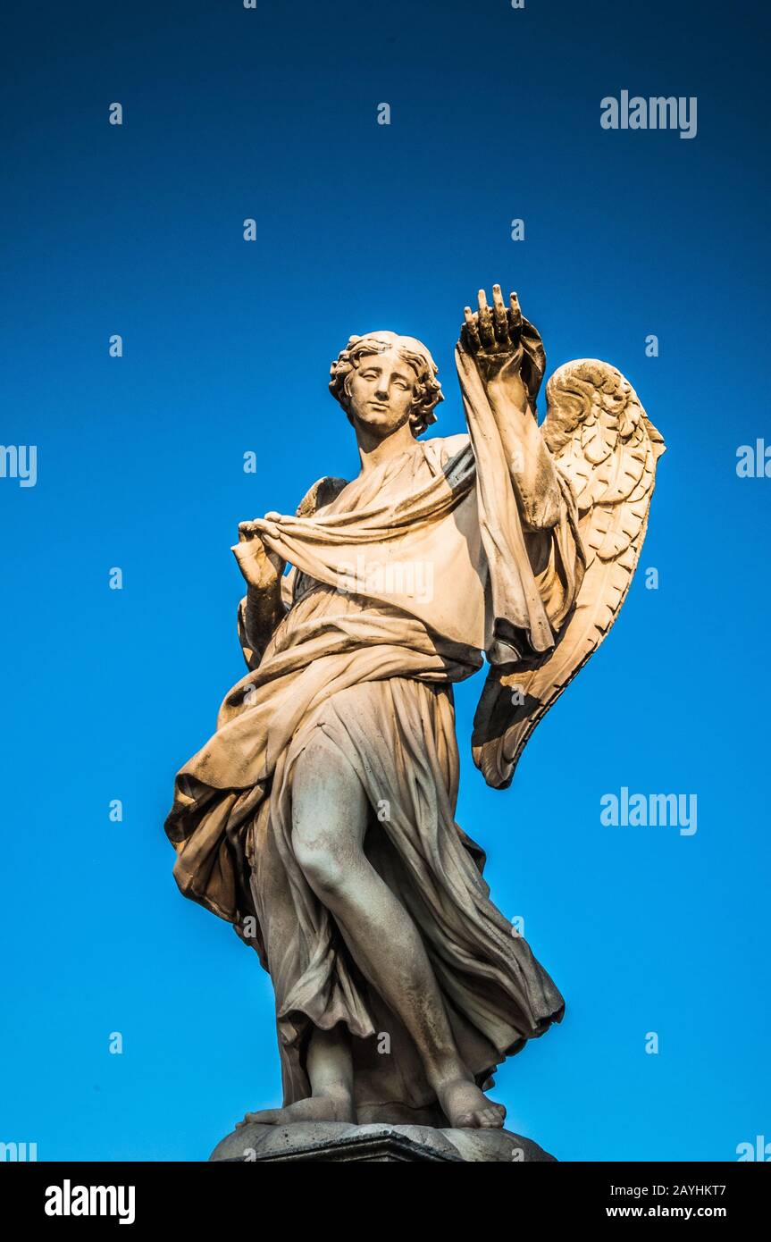 Ancient statue of the angel in the warm rays of sun with blue sky on ...