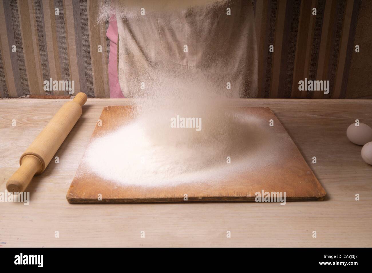 A woman sifts flour through a sieve. Plywood cutting board, wooden ...