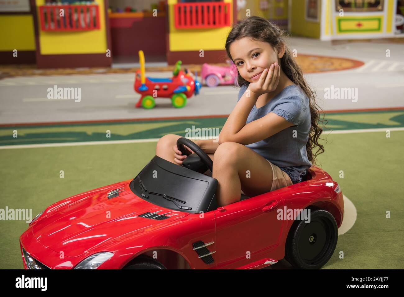 Cute child sitting in toy car at game room Stock Photo - Alamy