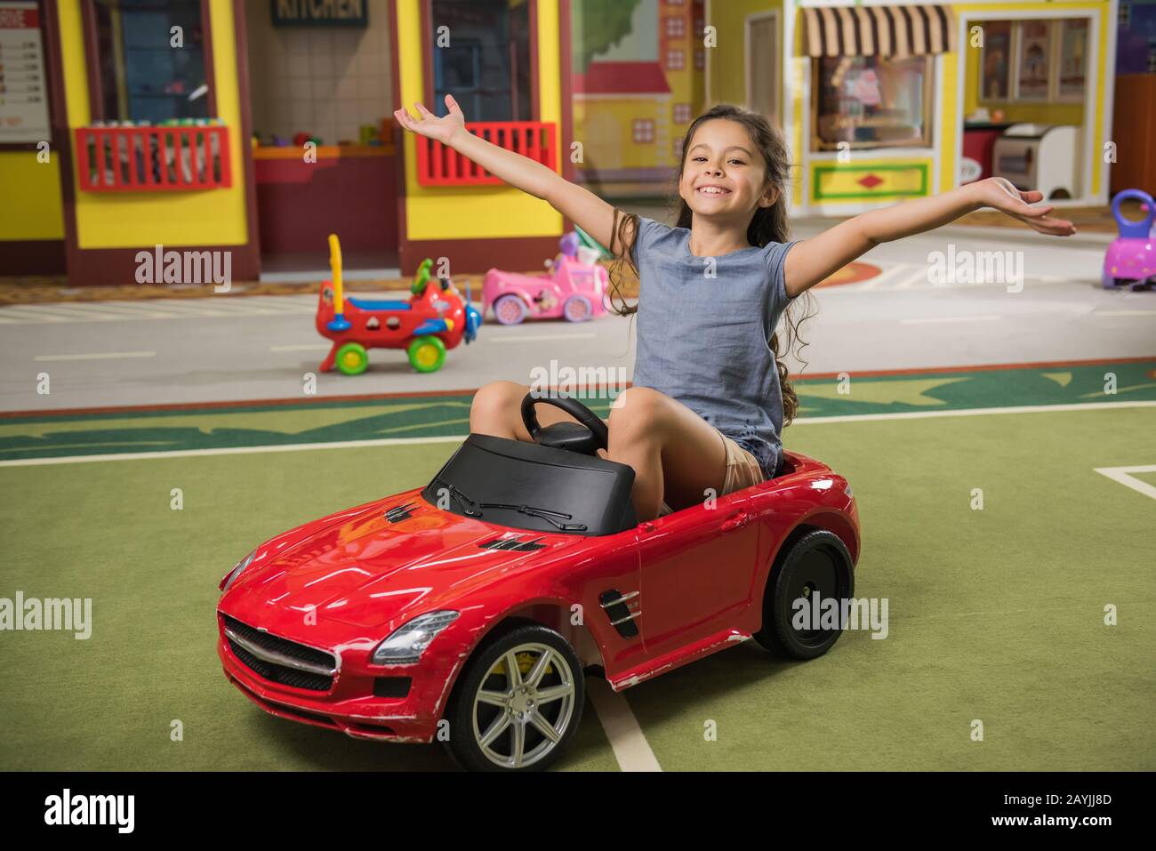 Happy little girl in toy car at game center Stock Photo - Alamy