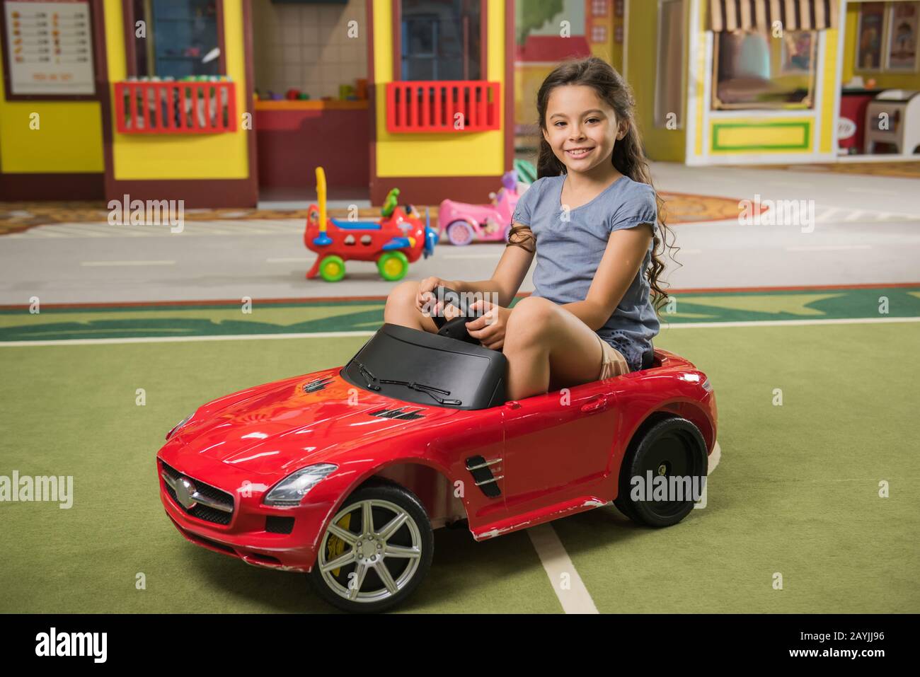 Happy kid sitting in mini toy car at playroom Stock Photo - Alamy