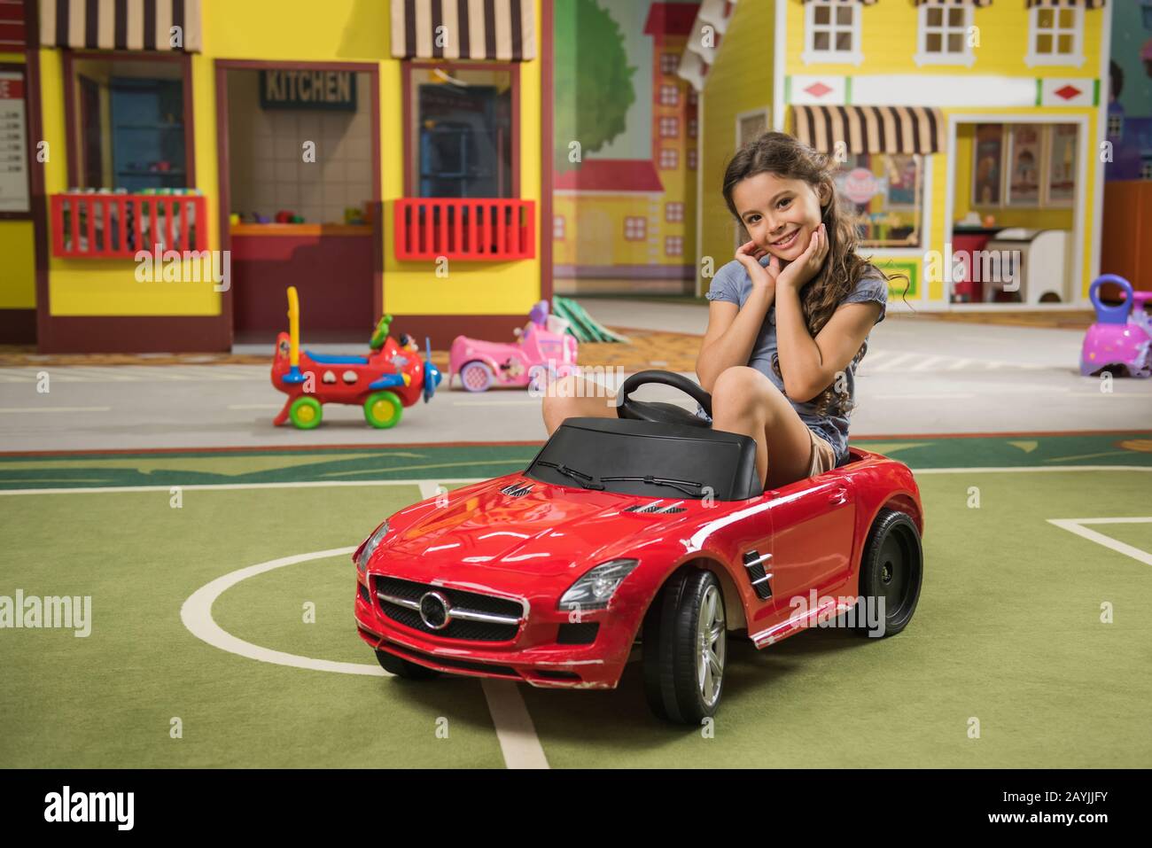 Pretty little girl with mini car at game center Stock Photo - Alamy