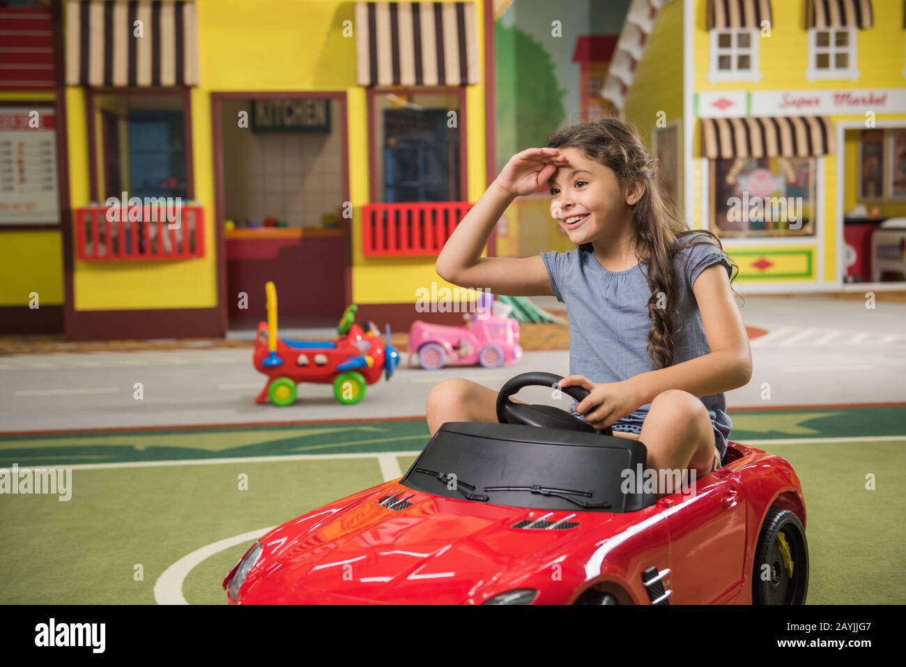 Girl playing with toy car in game center Stock Photo - Alamy