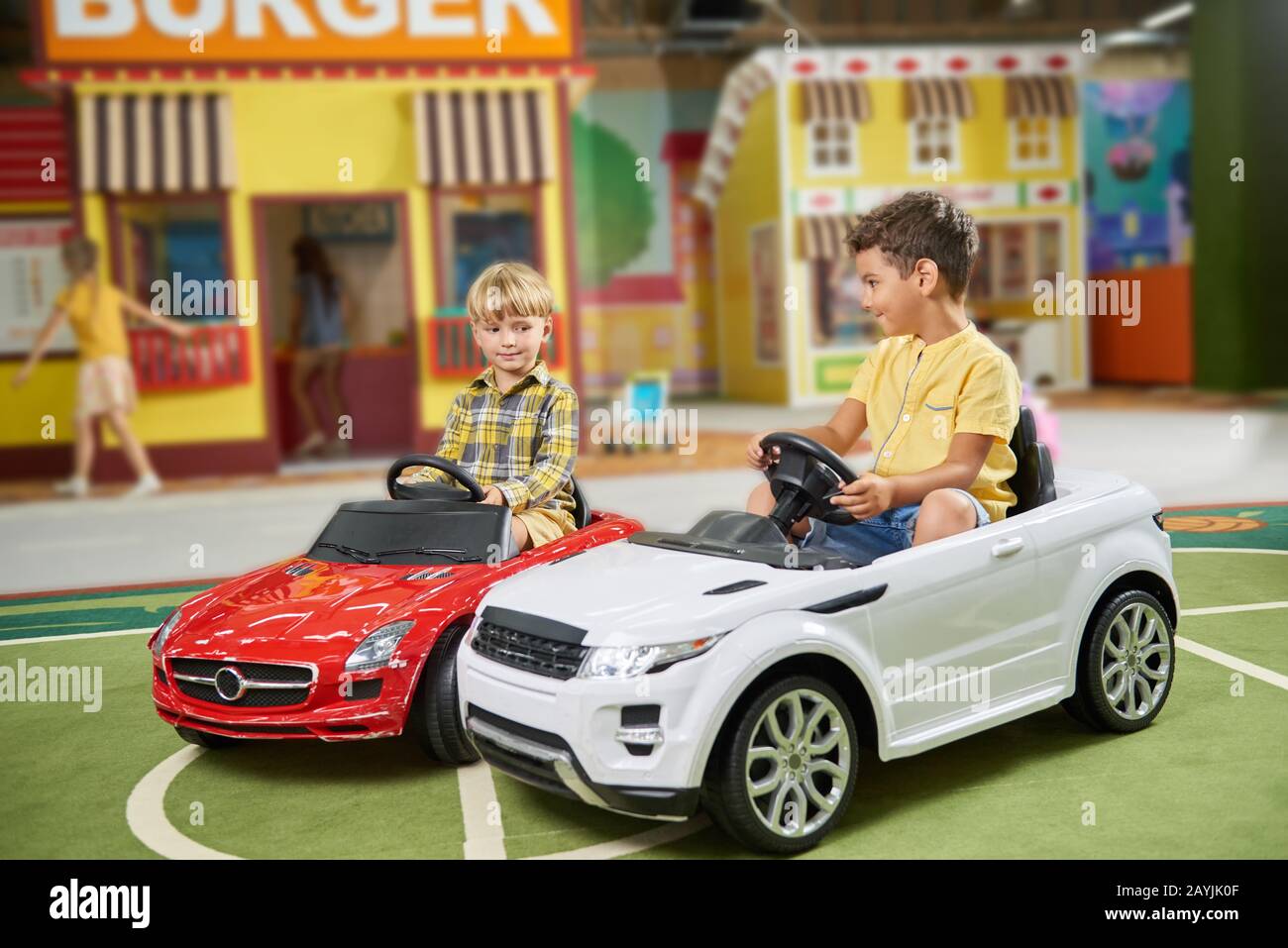 Two preschool boys ride on toy car in playground Stock Photo - Alamy