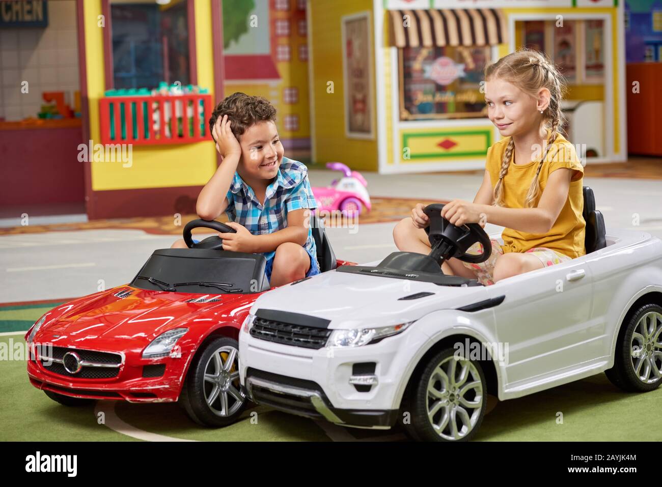 Happy kids sitting in toy cars in nursery school Stock Photo - Alamy