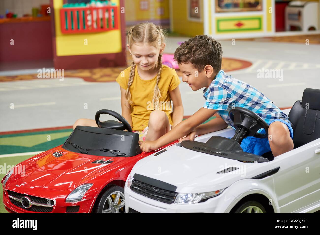 Young boy and girl ride on toy car in playground Stock Photo - Alamy