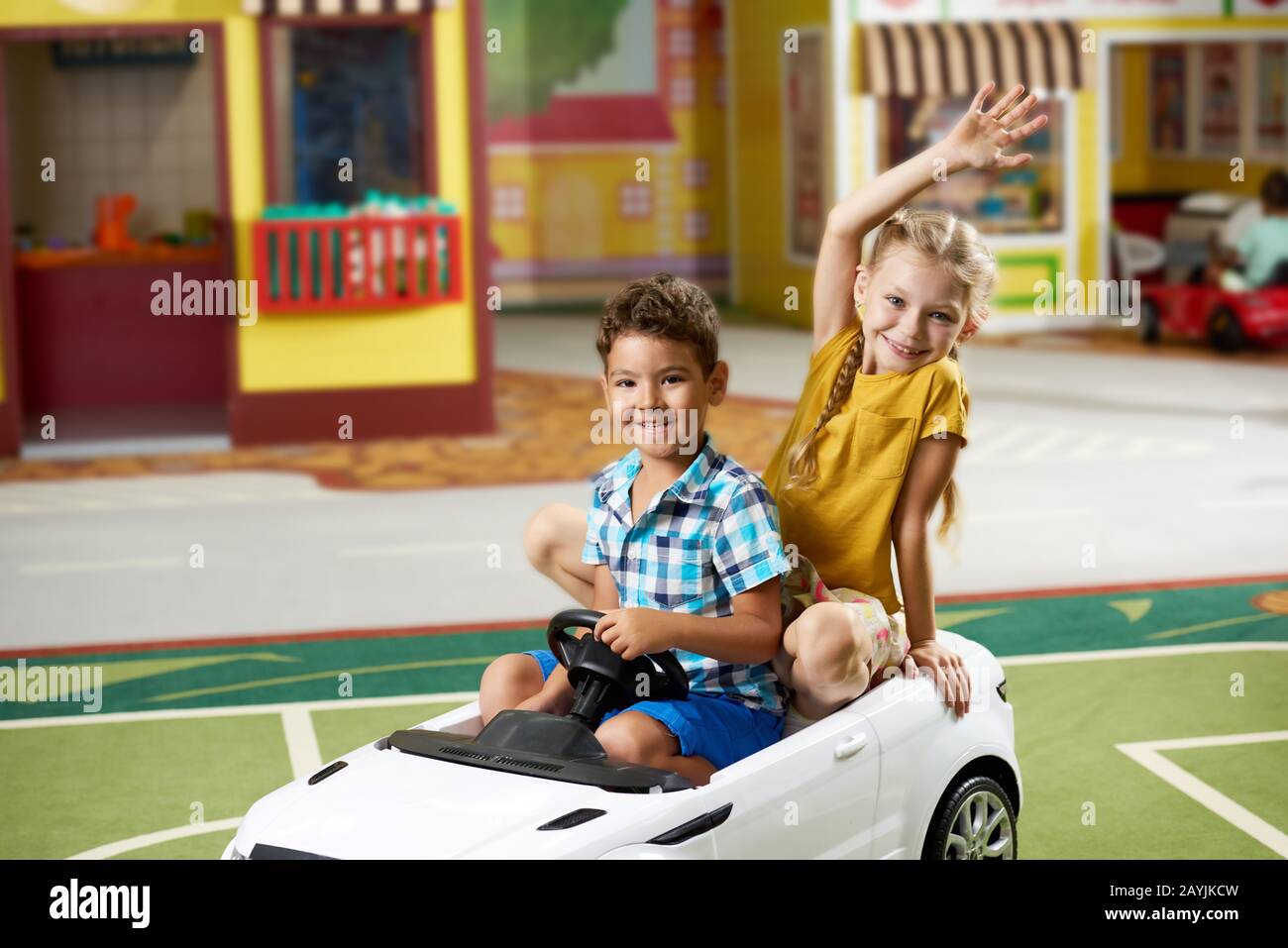 Happy kids sitting in toy cars in nursery school Stock Photo - Alamy