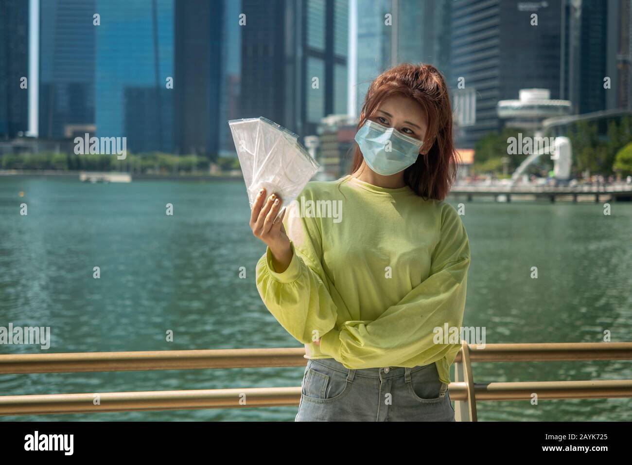 Asian Chinese girl wearing a surgical face mask and holding extra face ...