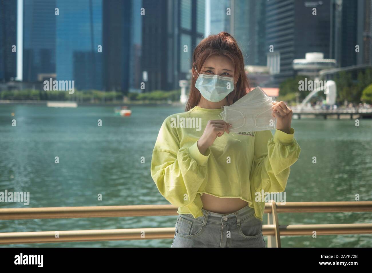 Asian Chinese girl wearing a surgical face mask and holding extra face ...