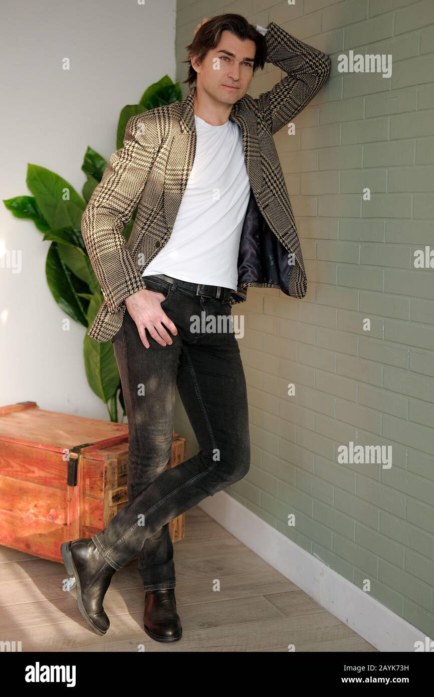 Tall handsome man standing next to grey wall and wooden box Stock Photo ...