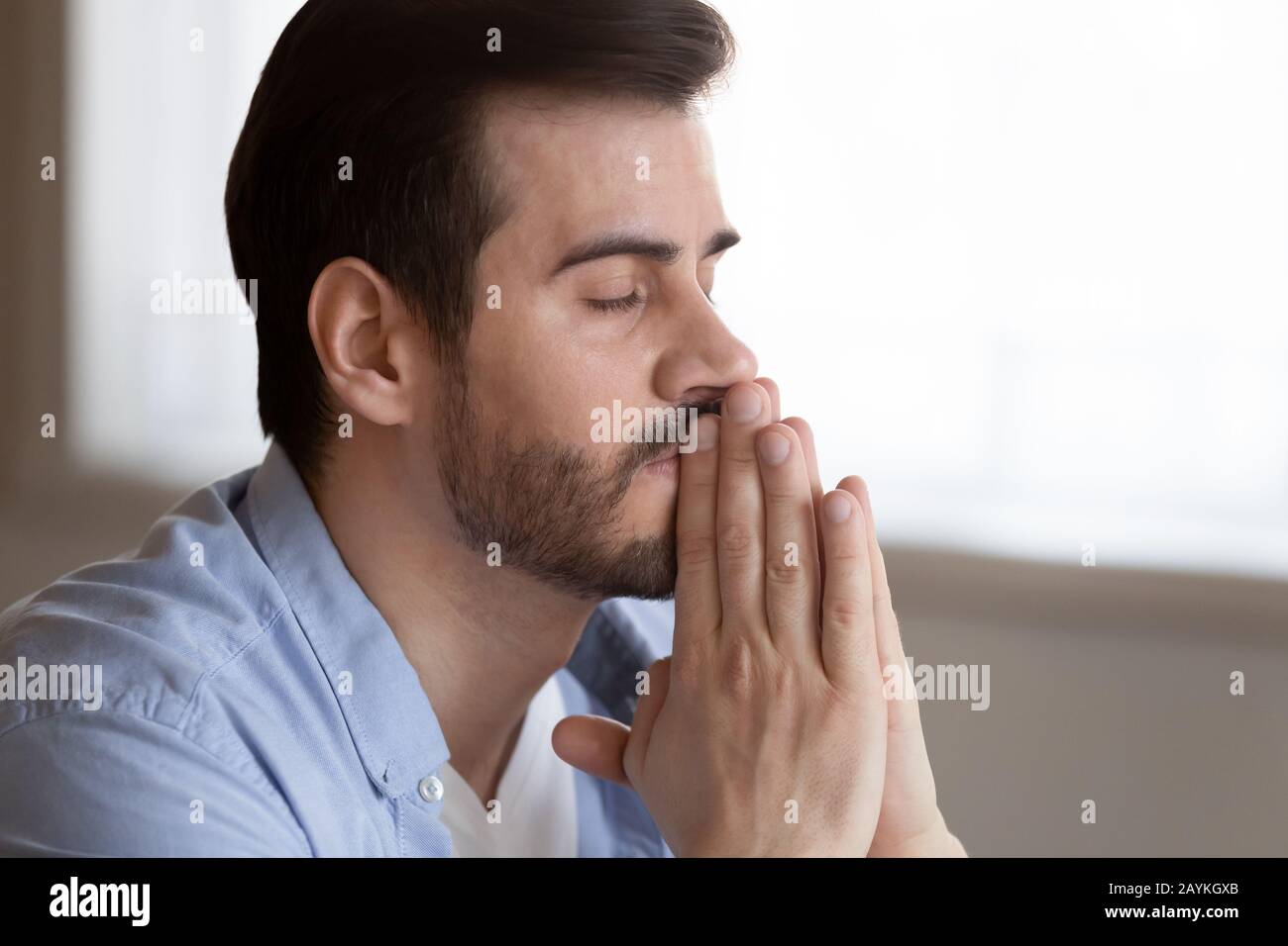Hopeful man with hands in prayer ask for best luck Stock Photo - Alamy