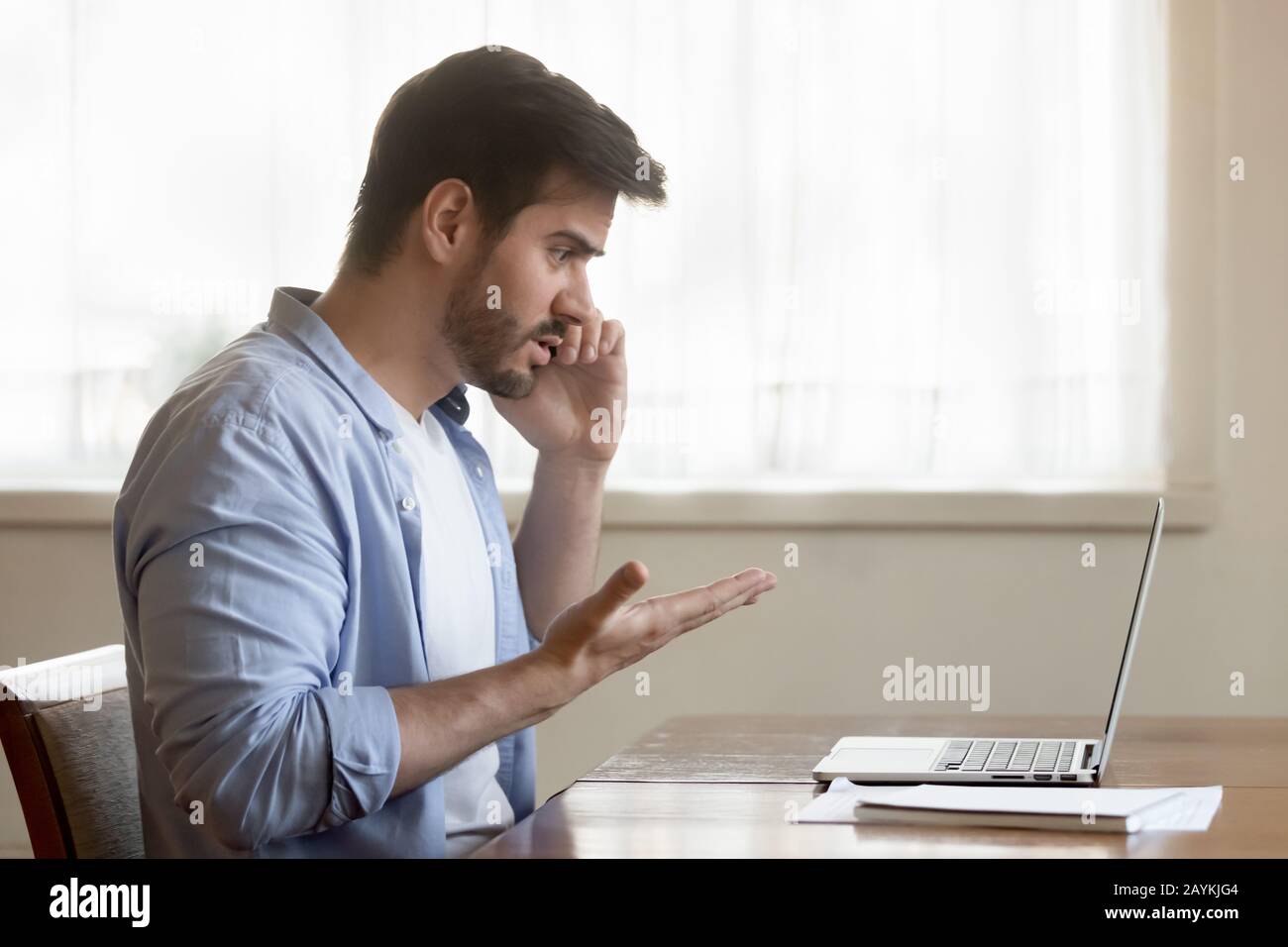Frustrated man talk on cell having laptop problems Stock Photo - Alamy