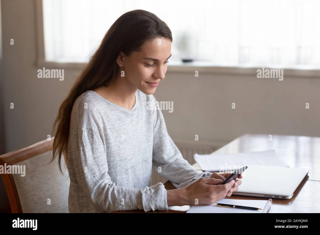 Millennial girl sit at table texting on smartphone Stock Photo - Alamy