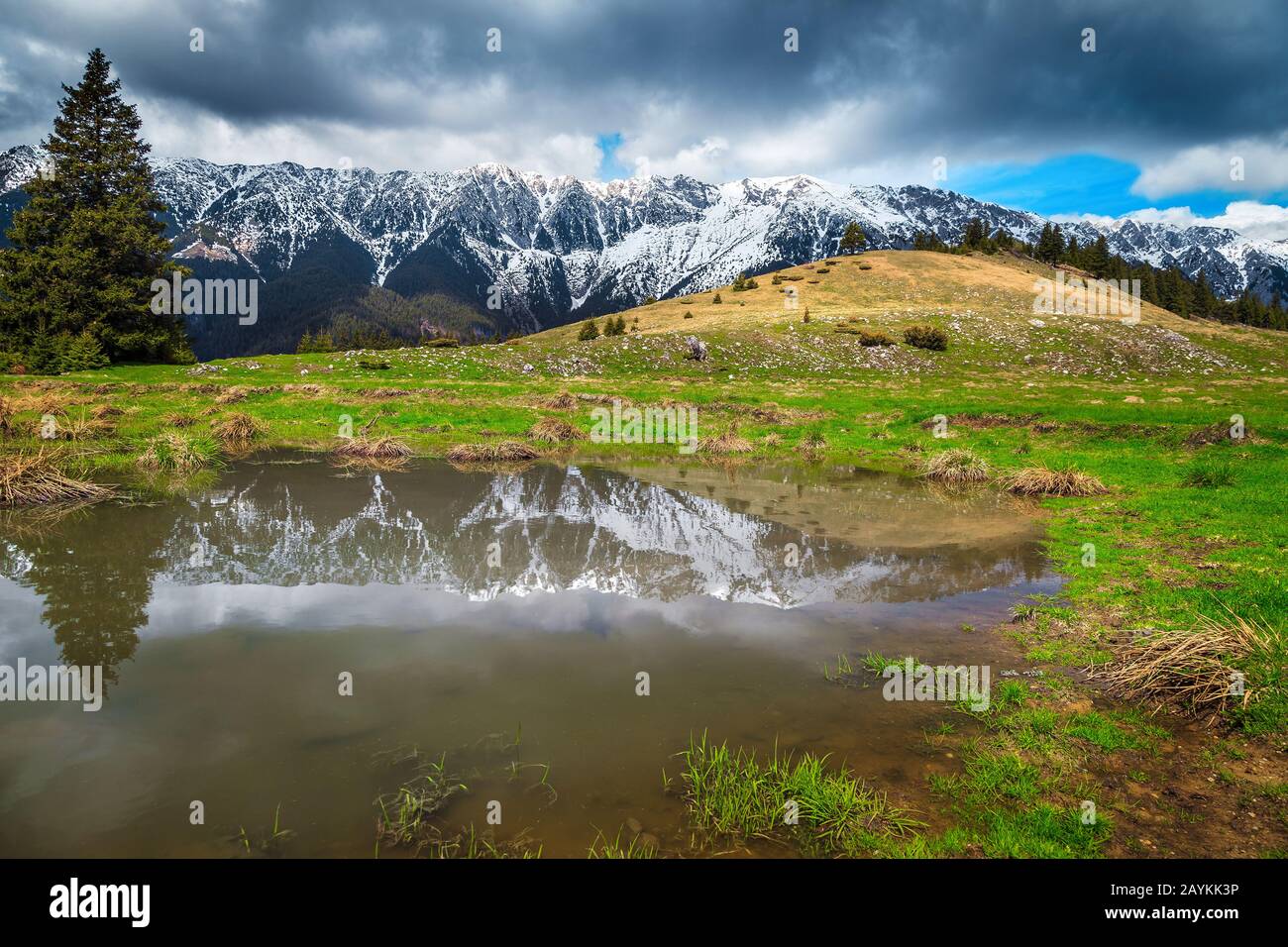 Beautiful alpine scenery with small lake and high snowy Piatra Craiului ...
