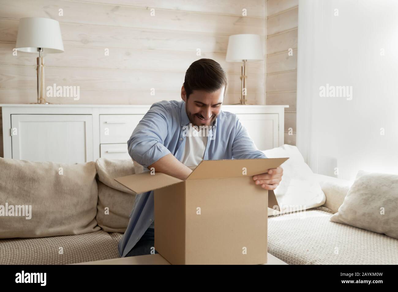 Excited male client unpack internet delivery package Stock Photo - Alamy