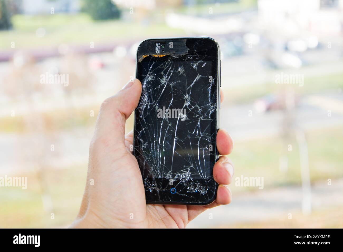 Broken glass screen smartphone in hand of upset man. The guy is holding ...