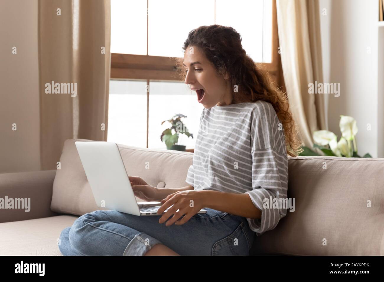 Surprised young woman looking at computer monitor with opened mouth ...
