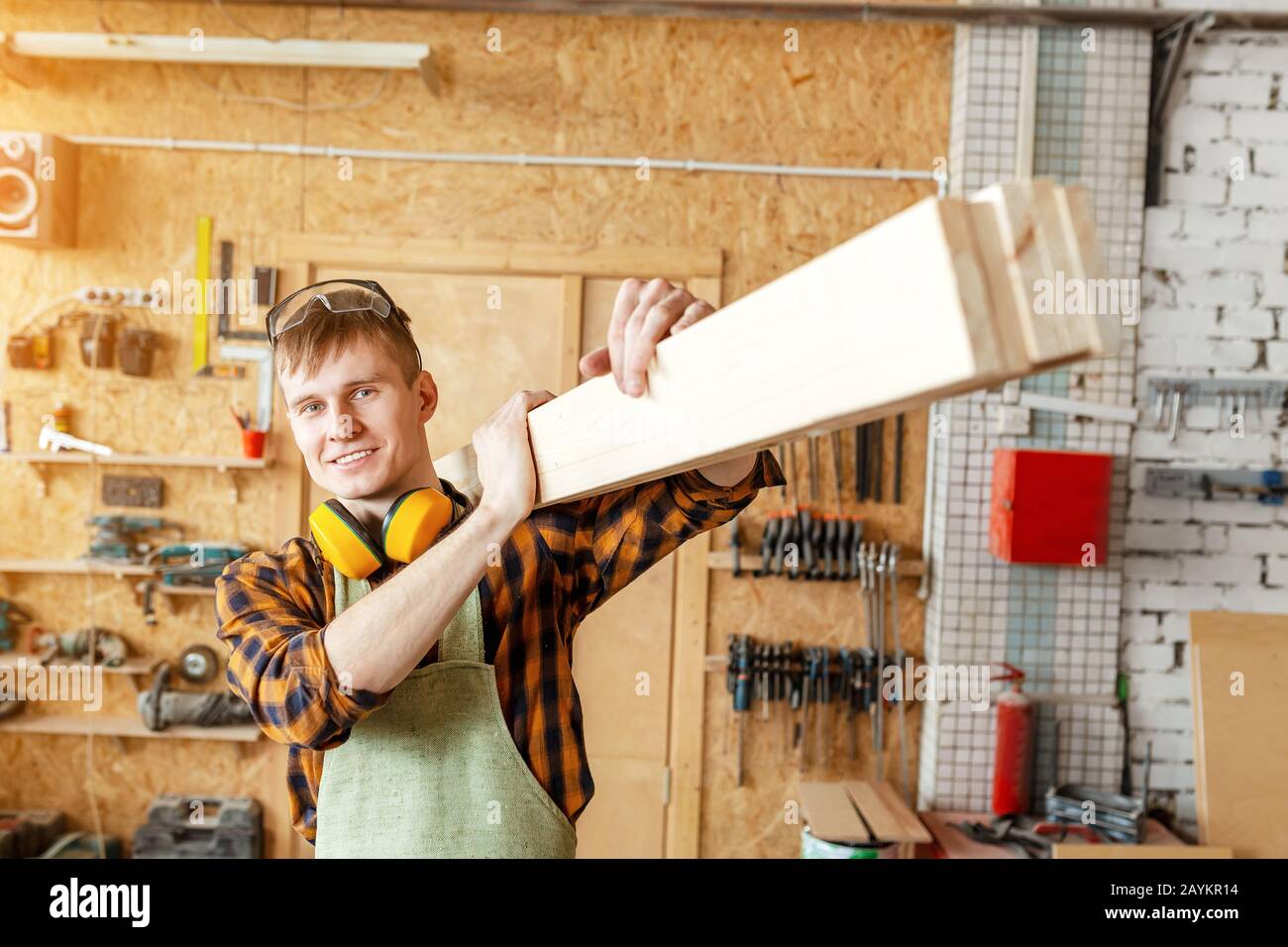 Happy carpenter man carrying a bunch of wooden planks. Handyman and ...