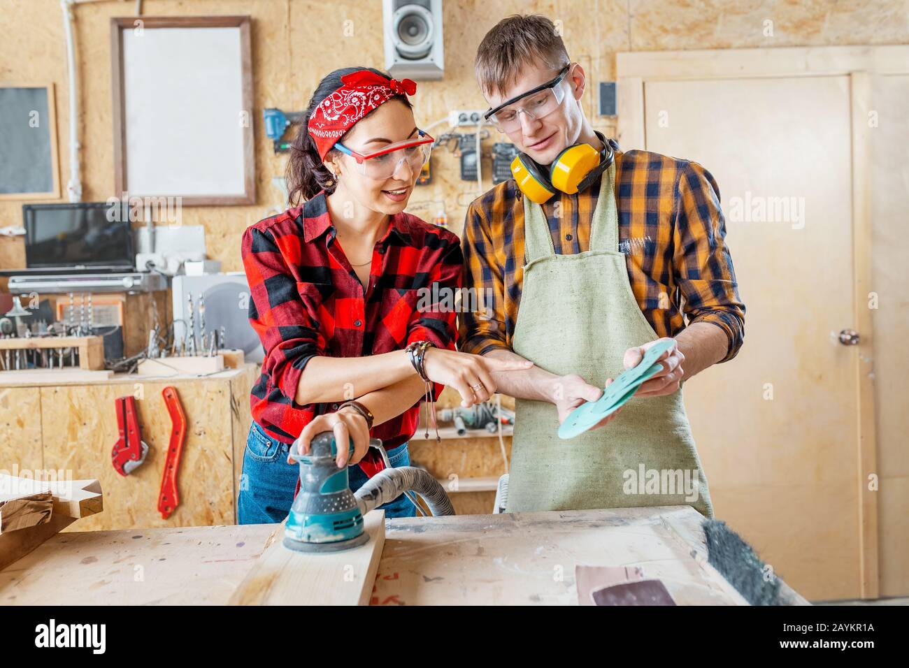 man and woman as a team working in the workshop with wood and polishing ...