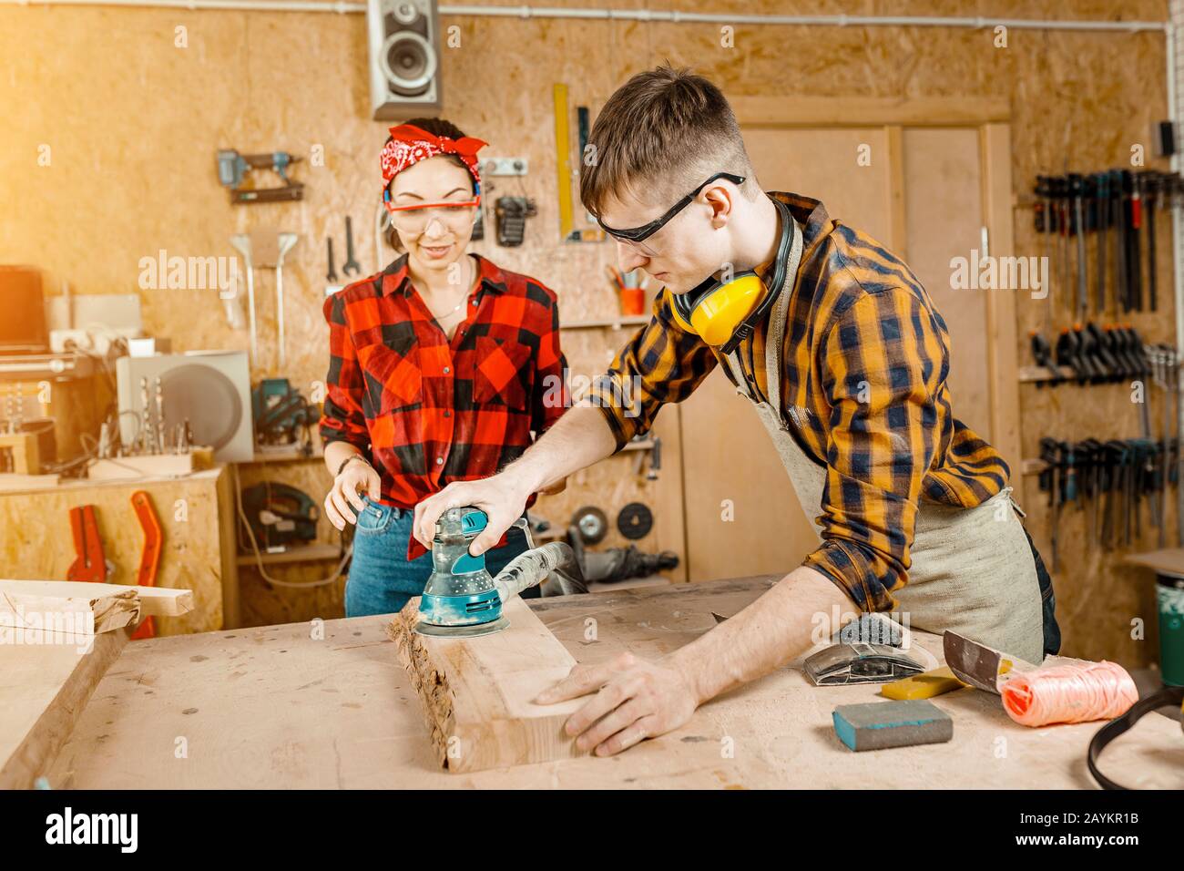 man and woman as a team working in the workshop with wood and polishing ...