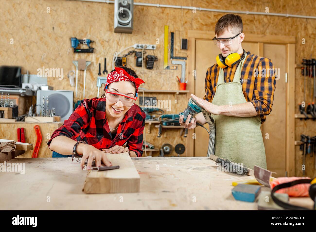 man and woman as a team working in the workshop with wood and polishing ...