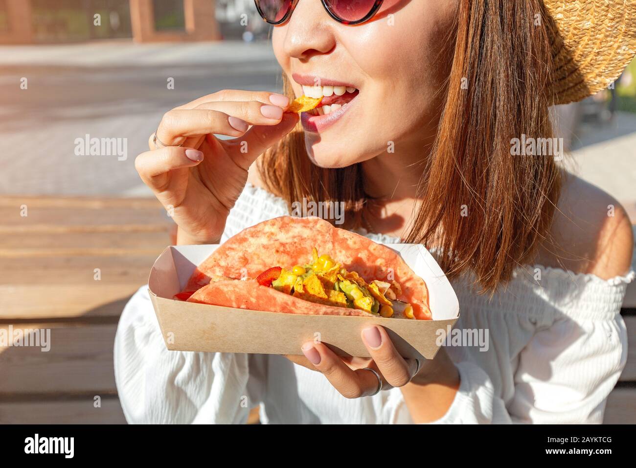Happy asian girl eating taco outside. Mexican fastfood cuisine. Tasty ...