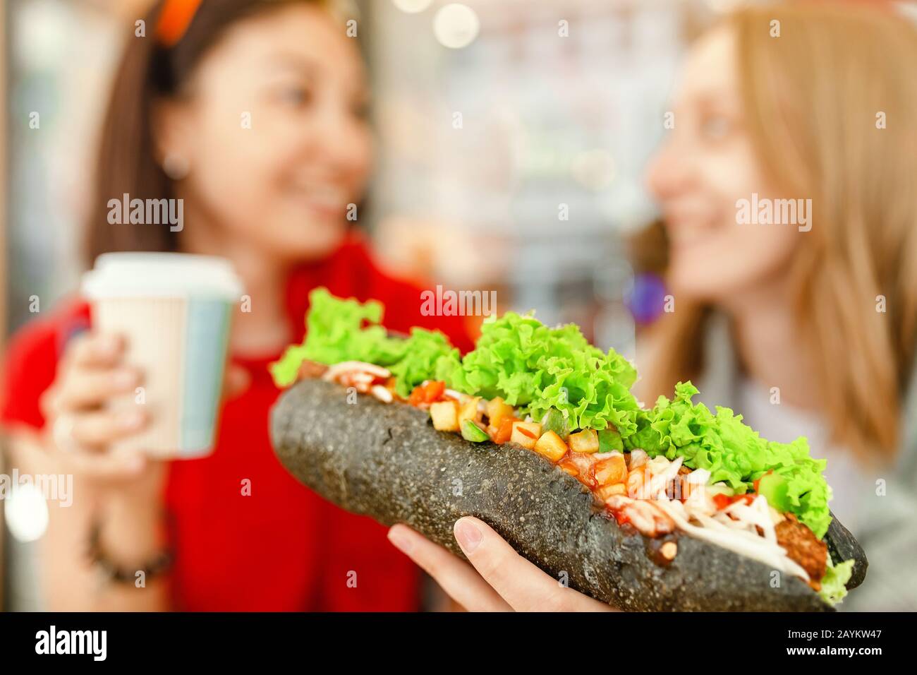 Cheerful multiracial friends eating sandwich and having fun in a cafe ...