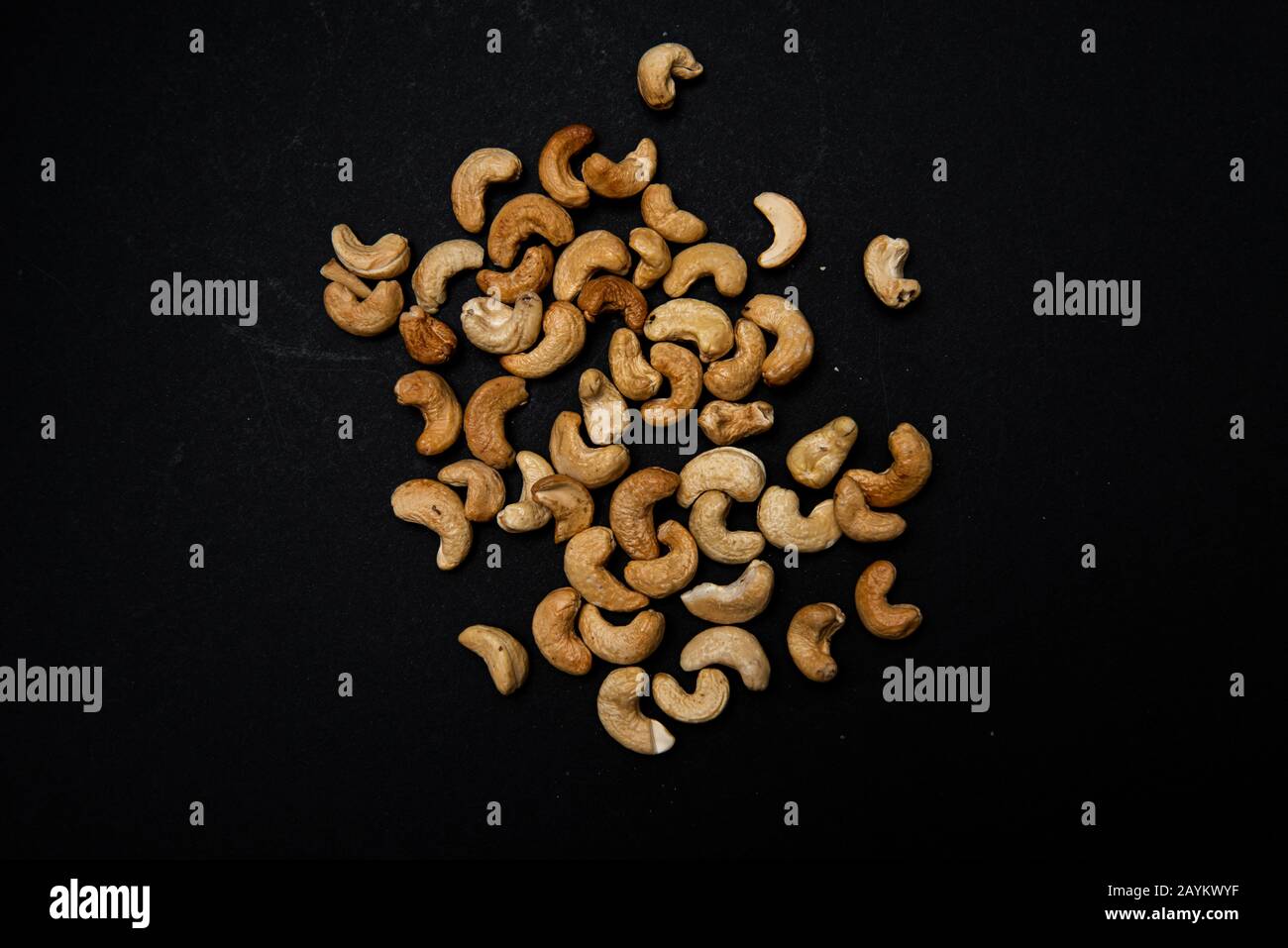 lots of fried cashews nuts scattered on black background with copy ...